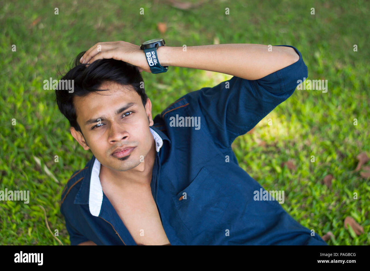 Closeup of a young man laying on grass and passing his hand through his ...
