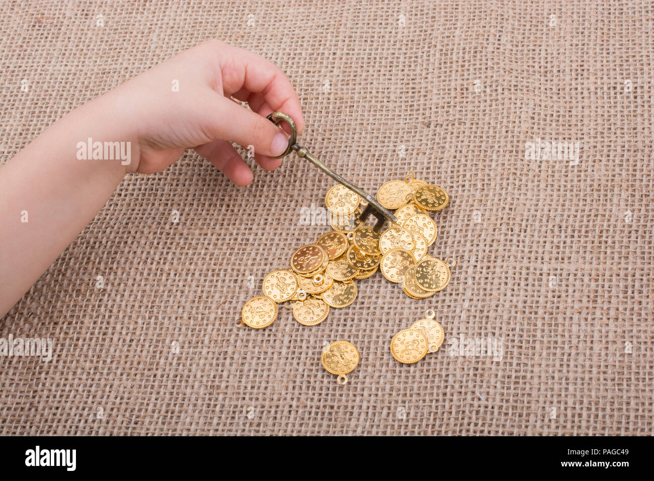 Hand holding a retro styled key over fake gold coins Stock Photo - Alamy