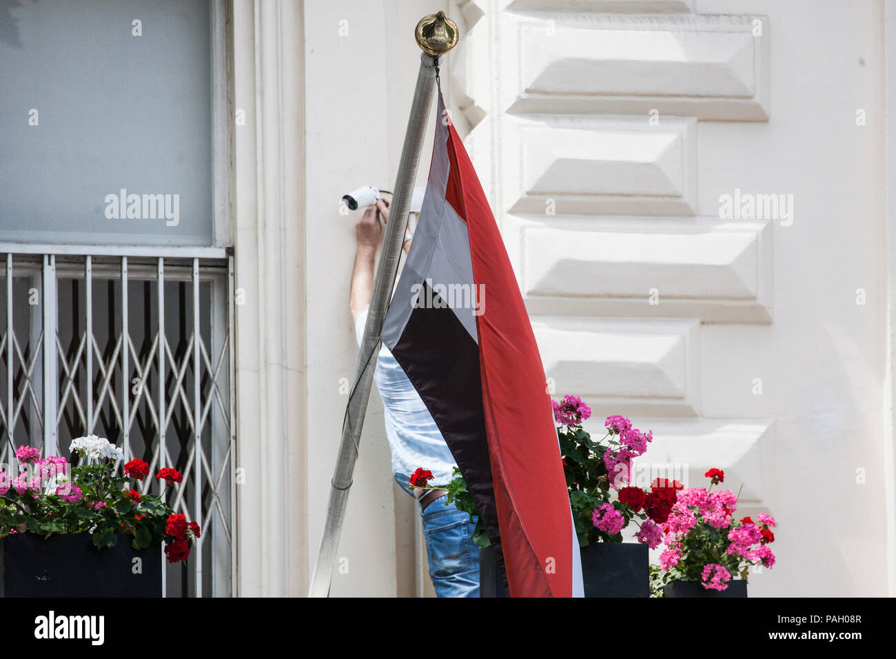 London, UK. 23rd July, 2018. A man adjusts a surveillance camera behind ...