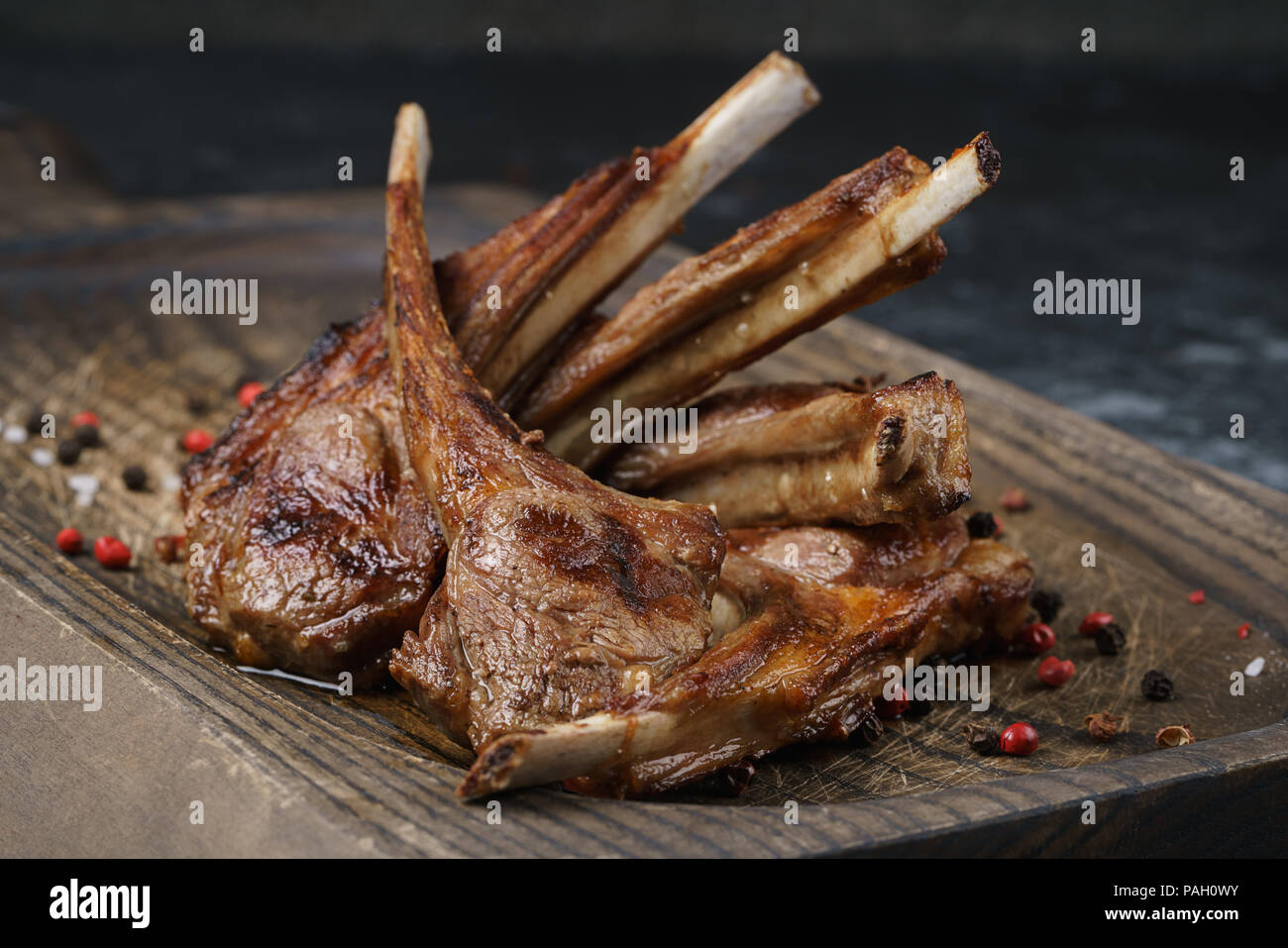 Roasted lamb ribs with spices and garlic on dark textural background ...