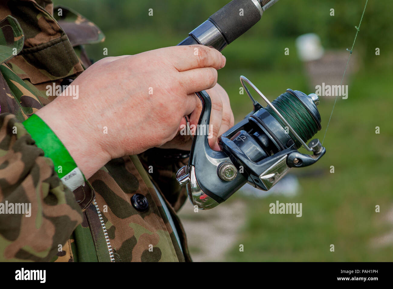 A fisherman with a fishing rod. Close-up of a hand holding a spinning ...