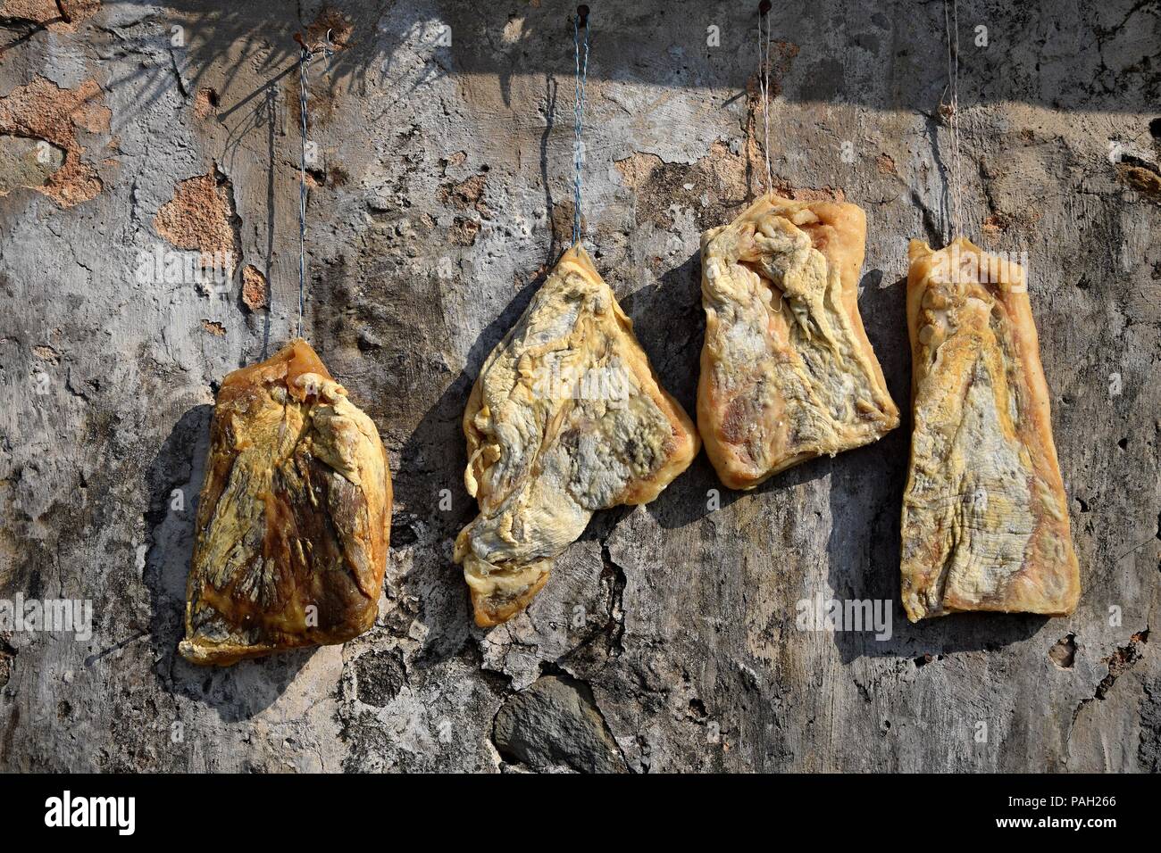 The pieces of the meat hung on the wall for the sun-dry Stock Photo - Alamy