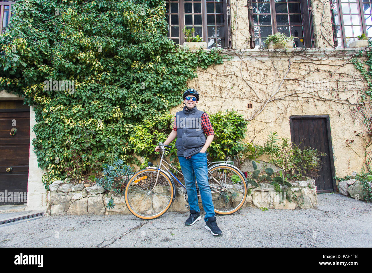 Handsome guy cyclist in cycling clothes and helmet posing near bicycle ...