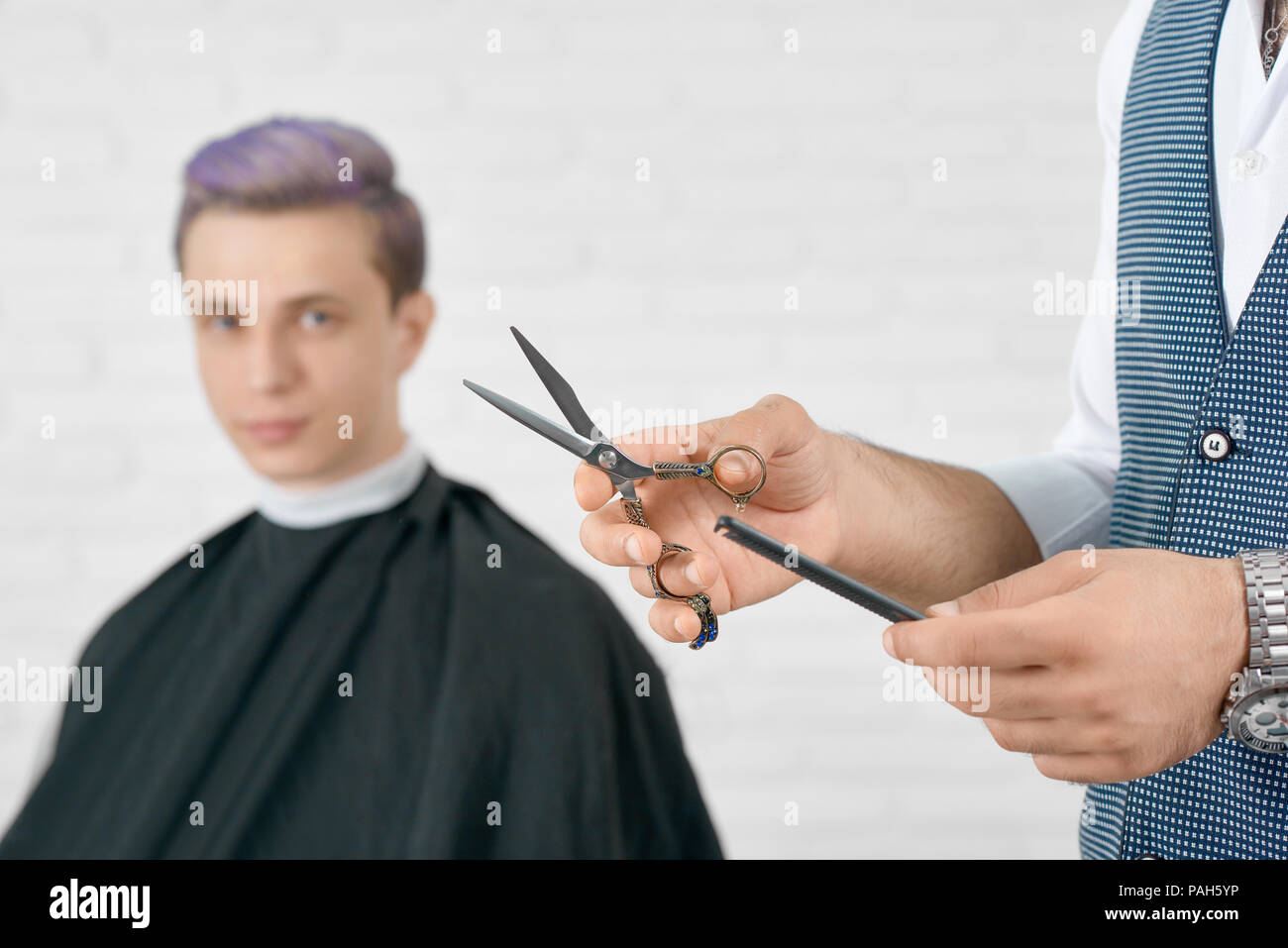Barber's hands holding metallic scissors and black plastic comb. Young ...