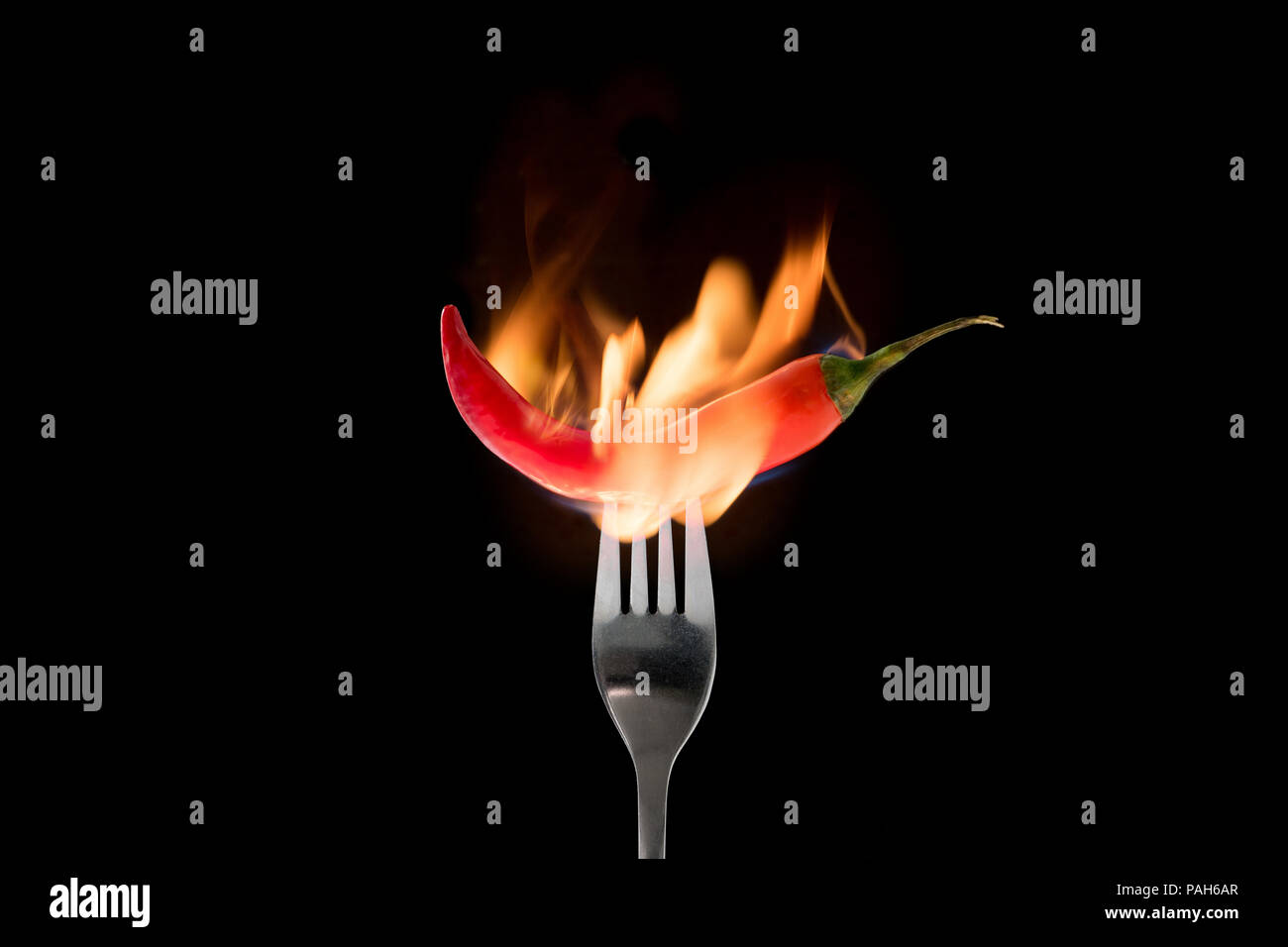 Hot hot red pepper on a fork fire burning on a black background Stock ...