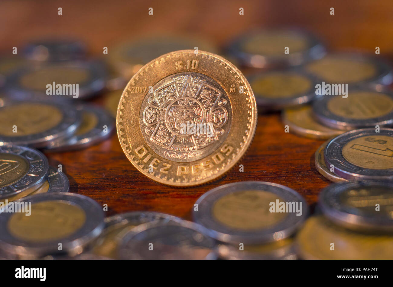 Mexican Coin in the middle of other coins in a table of wood suggesting ...