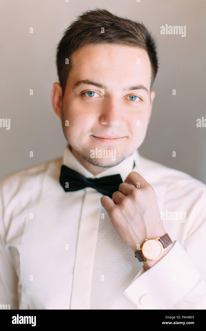 Close-up portrait of the smiling groom correcting the bow-tie Stock ...