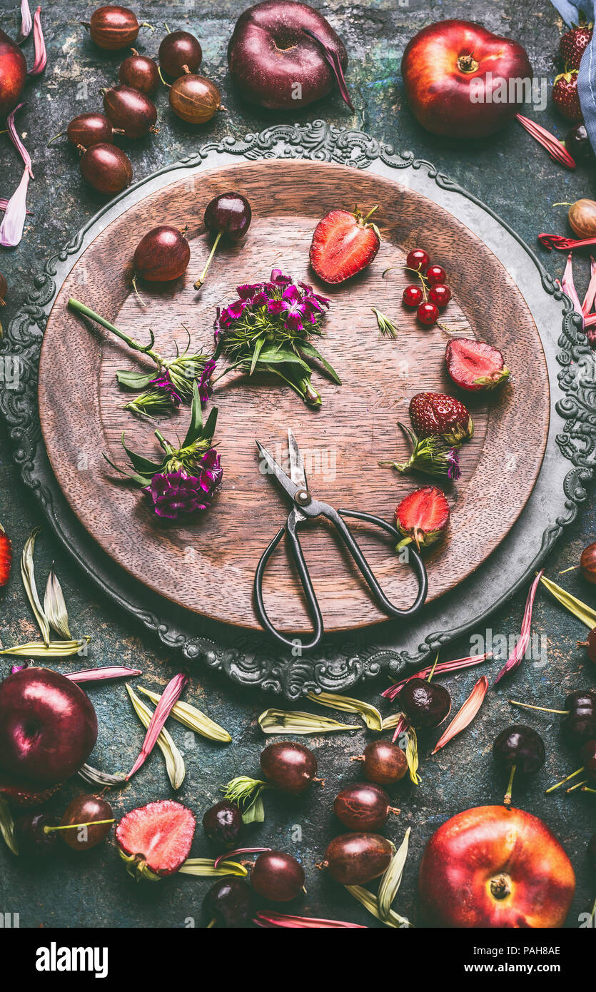 Wooden plate with seasonal fruits, berries, flowers and scissors on ...
