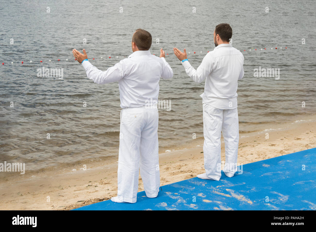 Two men praying. Two men in white clothes pray on the beach Stock Photo ...