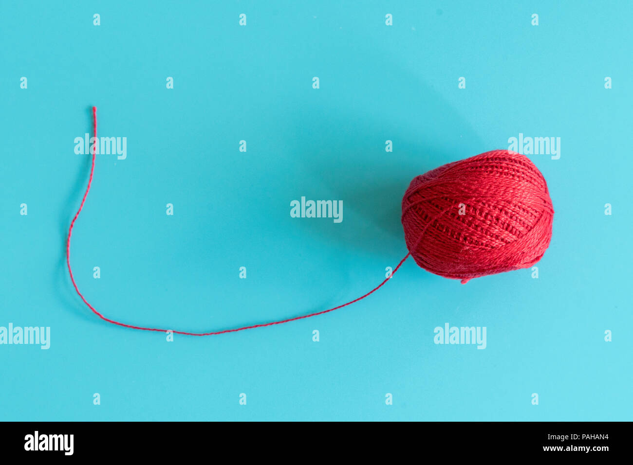 Red tangle of thread on a blue background Stock Photo - Alamy