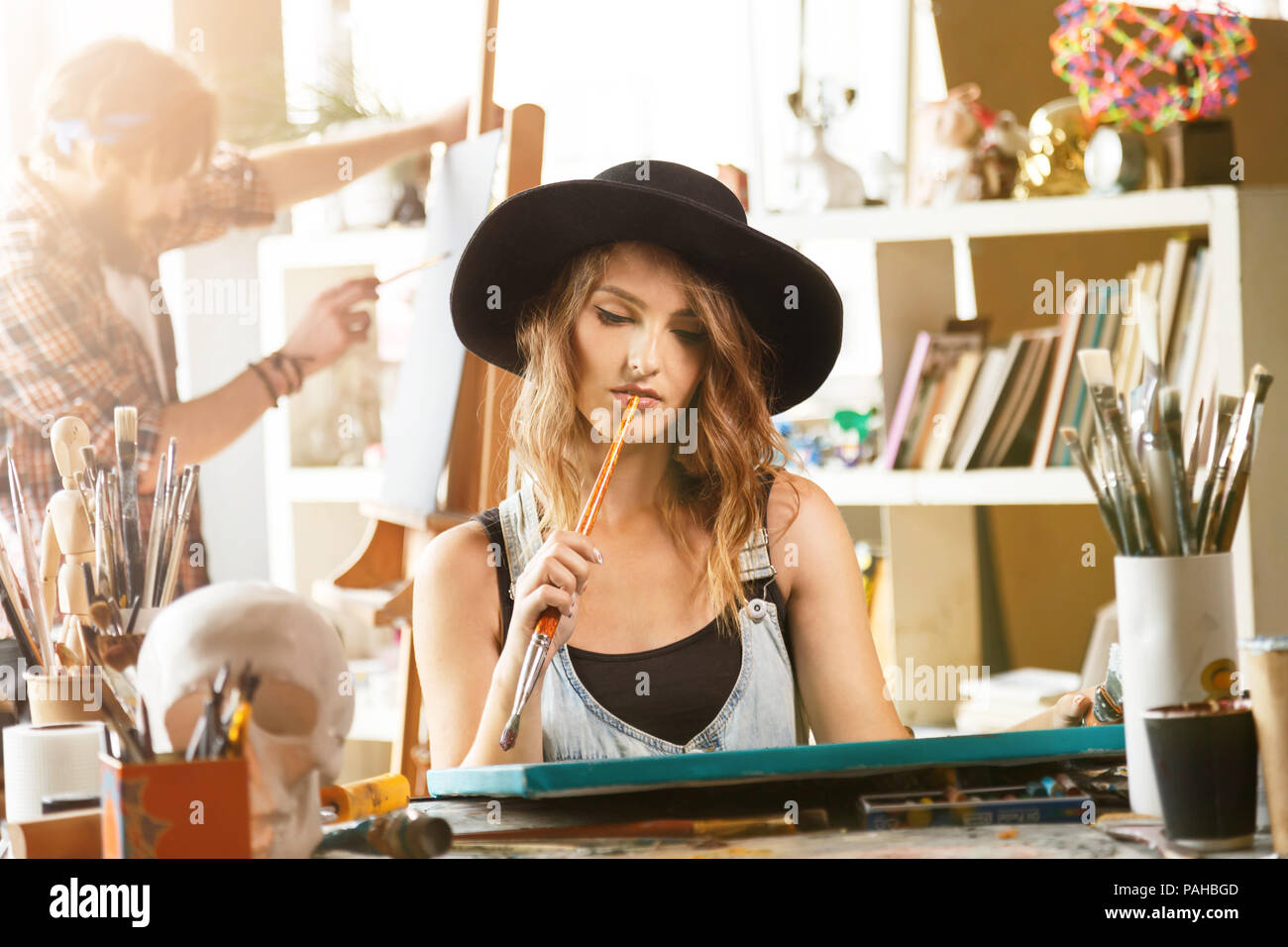 Female long hair artist in cute balck hat sitting and contemplate in ...