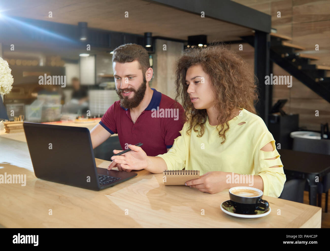 Couple of students studying in cafe using laptop. Drinking coffee ...