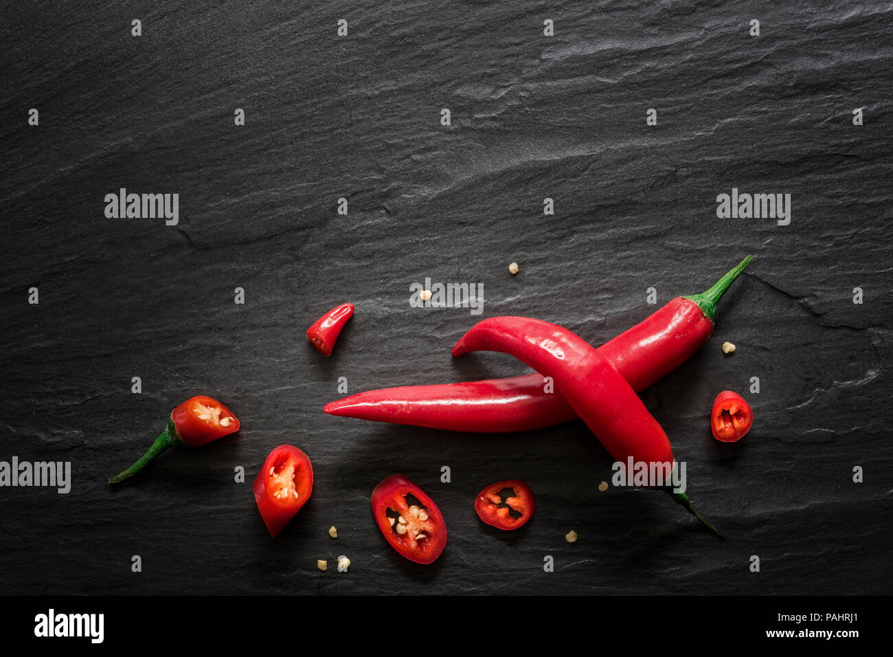 Red spicy chili peppers over dark slate. Food background, overhead view ...