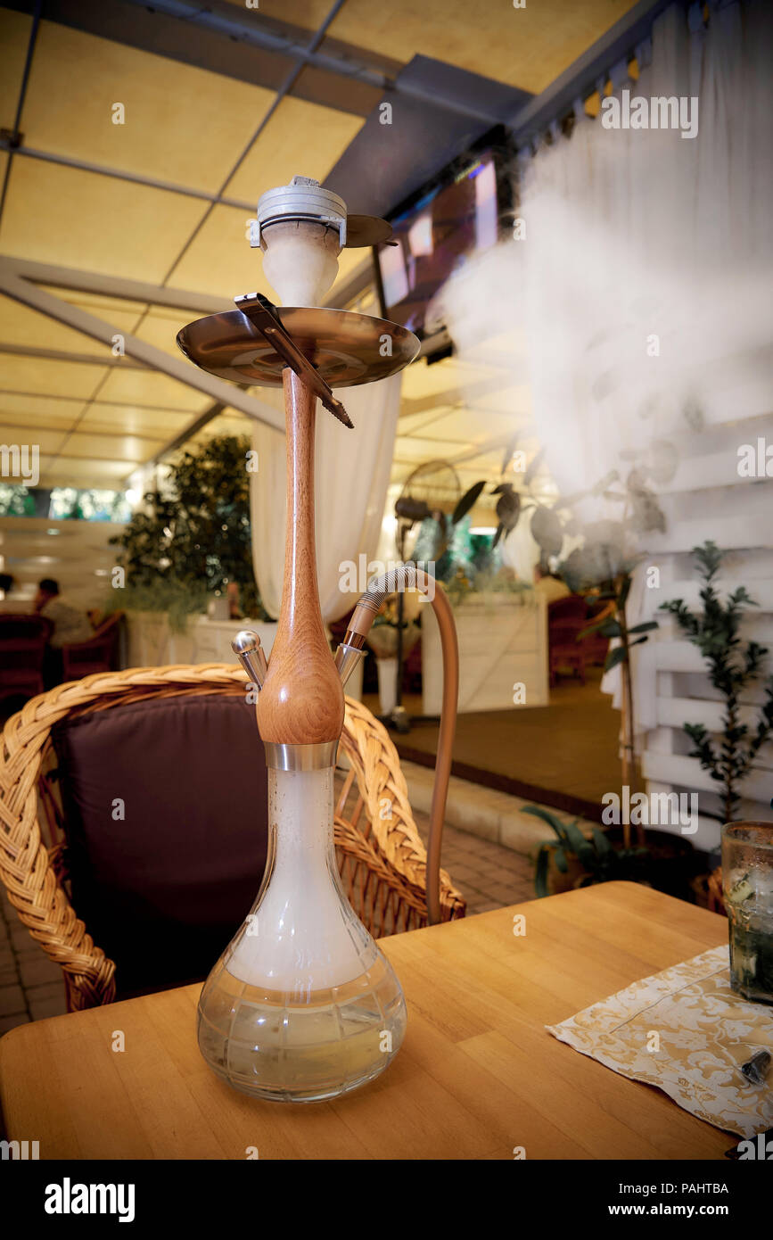 Hookah with a cloud of smoke on a table in a summer restaurant Stock ...