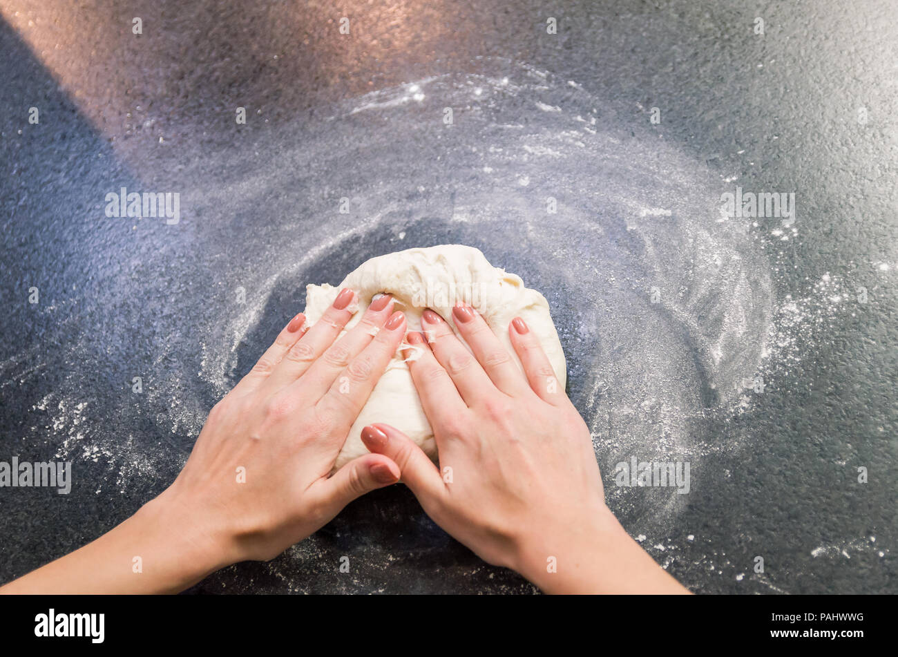 Woman preparing pizza dough on black granite table Stock Photo - Alamy