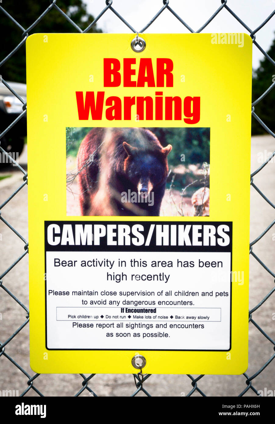 A bear warning sign hangs on a cyclone fence as an advisory to campers ...