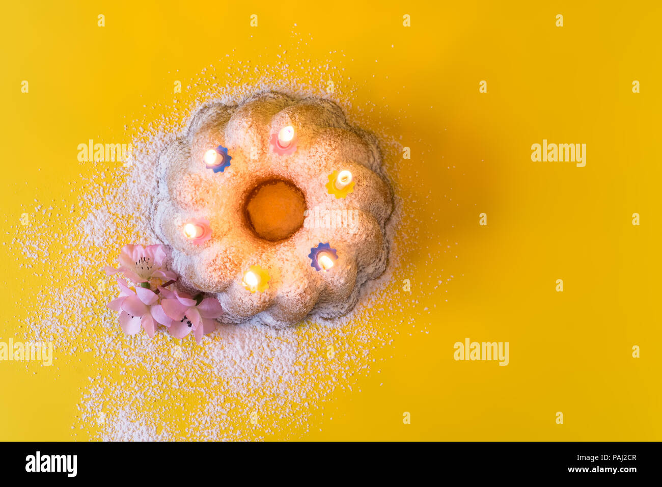 Homemade lemon ring cake with icing sugar and burning candles for ...
