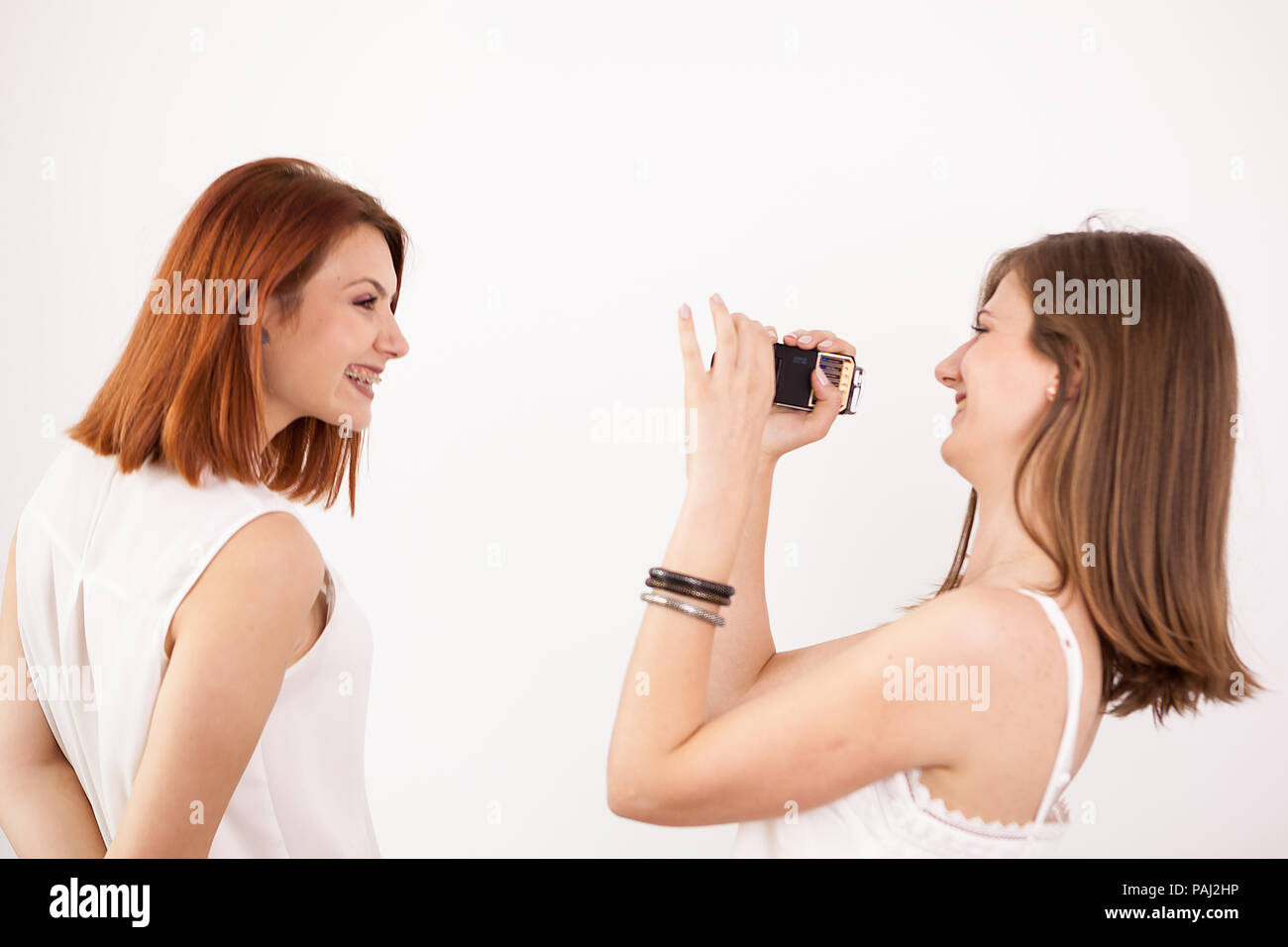 Two female friends playing with an action camera in studio over a white ...