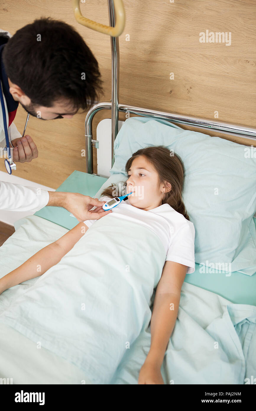 Doctor taking body temperature of her patient in hospital room Stock ...