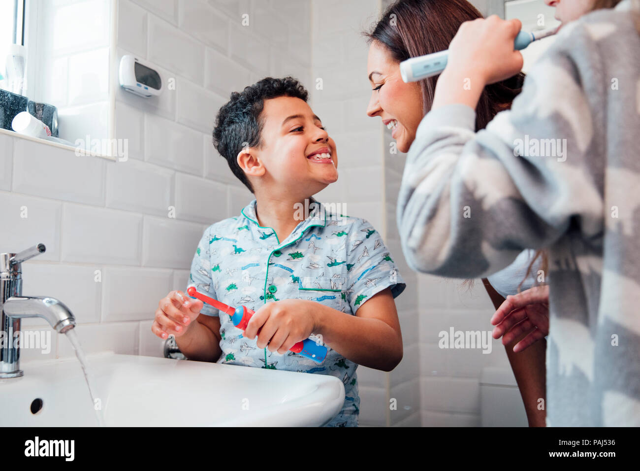 Children are brushing their teeth in the bathroom at home. The mother ...