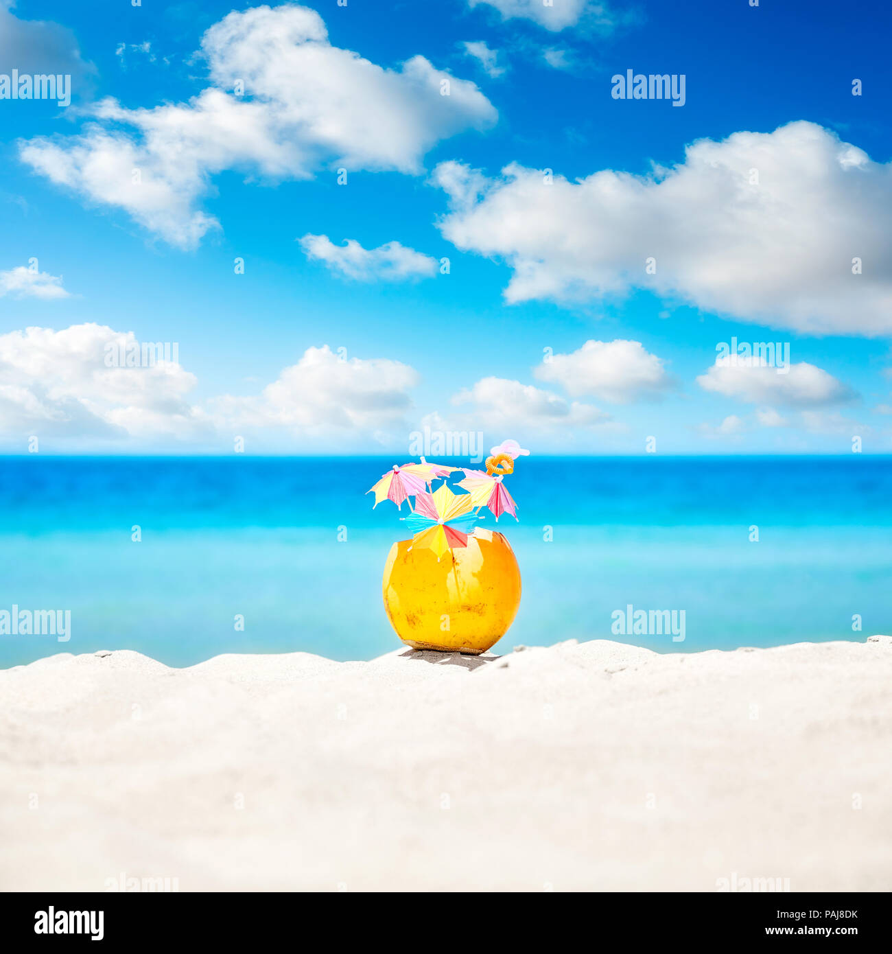 Coconut with colorful umbrellas and straws on a beach, summer fun ...