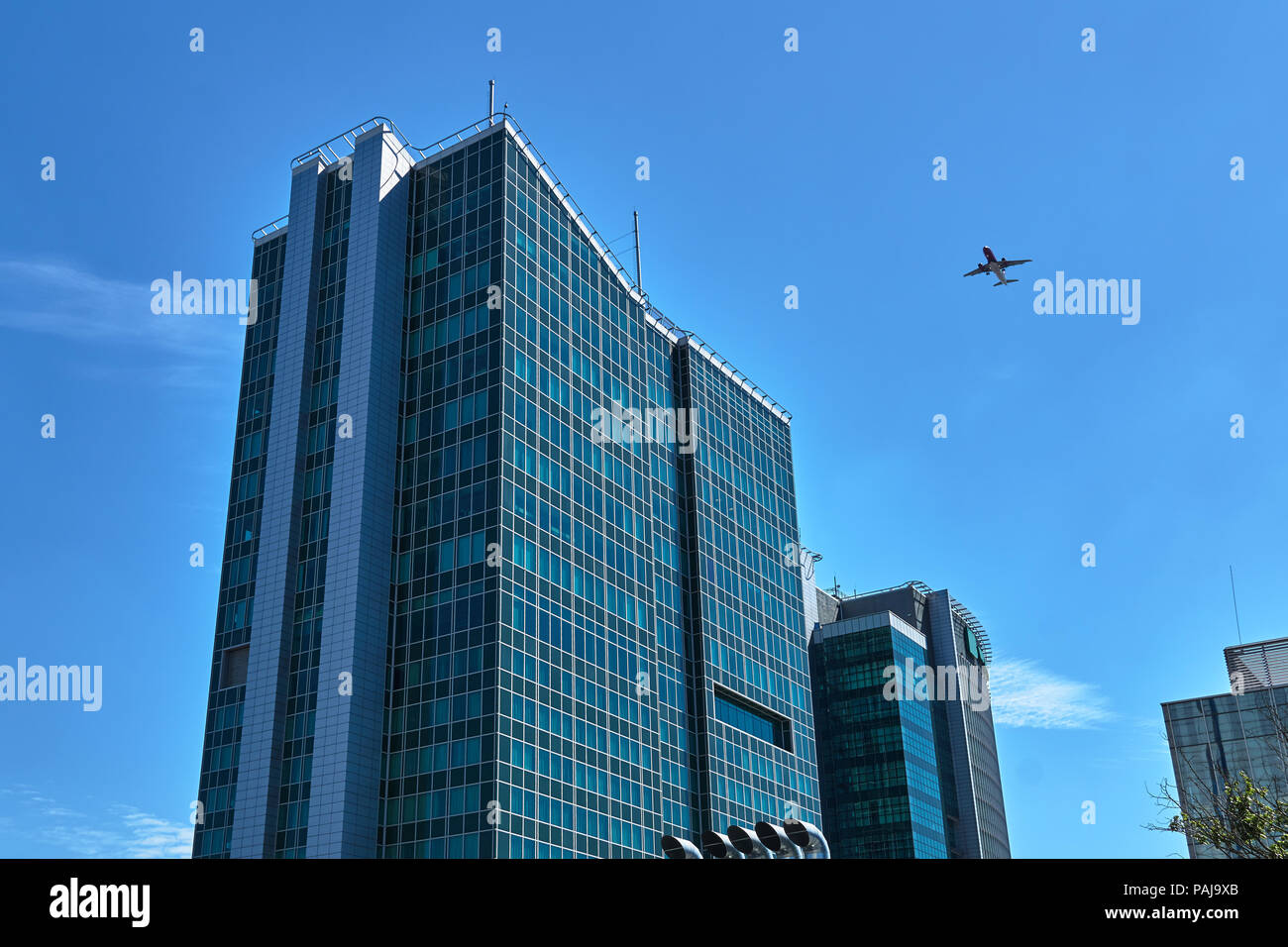 A plane flying over modern office buildings in Poznan Stock Photo - Alamy