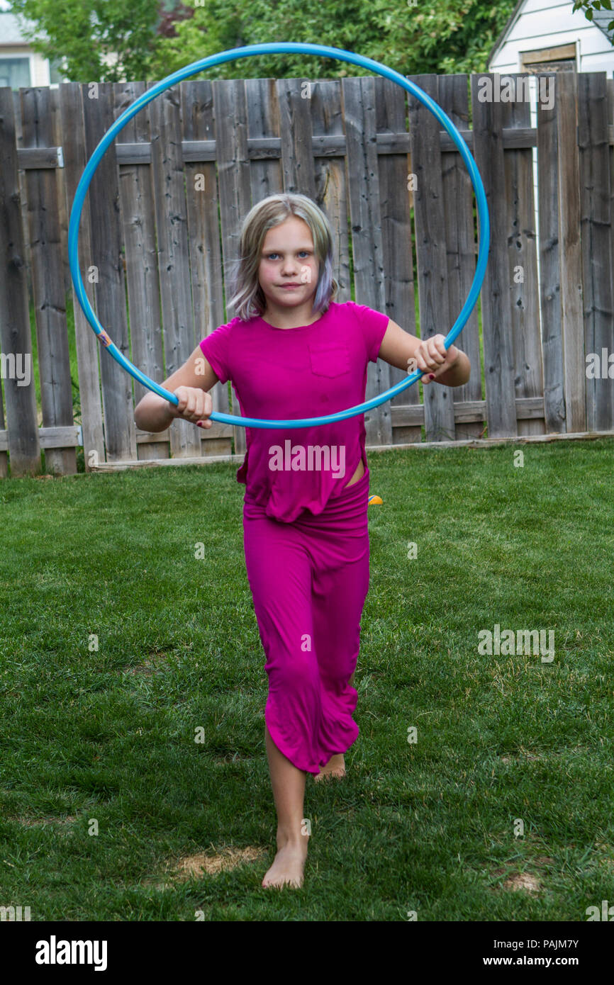 Pretty Blonde girl, playing with hula hoop, on the grass, in the back ...