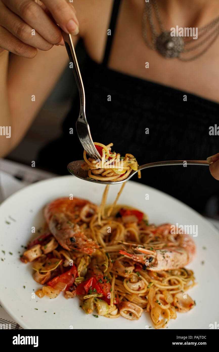 Woman eating seafood pasta with king prawns, shrimps and squids Stock ...