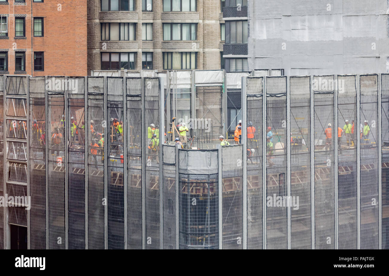 large group of construction workers working on a floor of a high rise ...