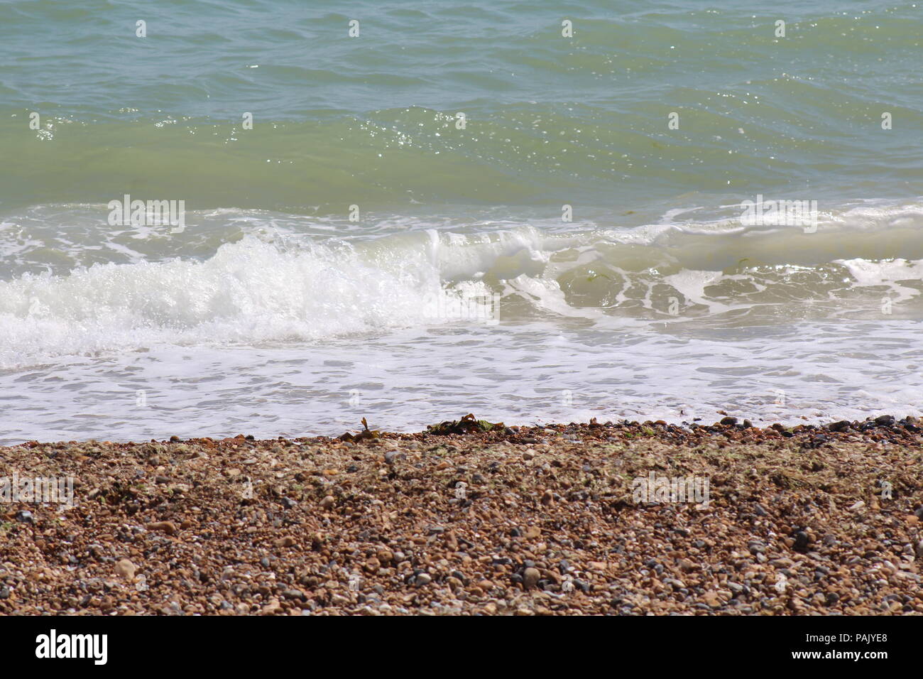 Tide coming in on pebble beach Stock Photo - Alamy