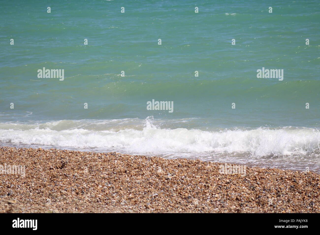 Tide coming in on pebble beach Stock Photo - Alamy