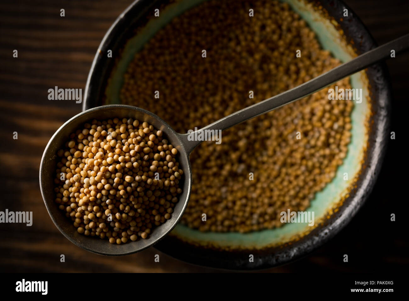 Raw, unprocessed mustard seed kernels in metal scoop on bowl with ...