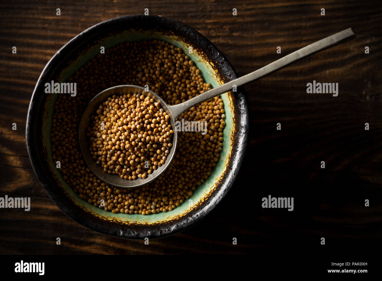 Raw, unprocessed mustard seed kernels in metal scoop on bowl with ...