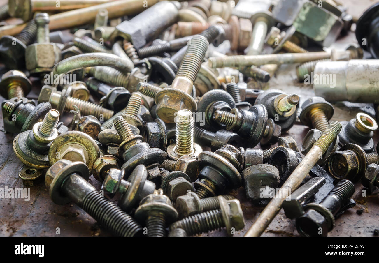 Bunch of dirty greasy screws on a wood table at a service workshop ...