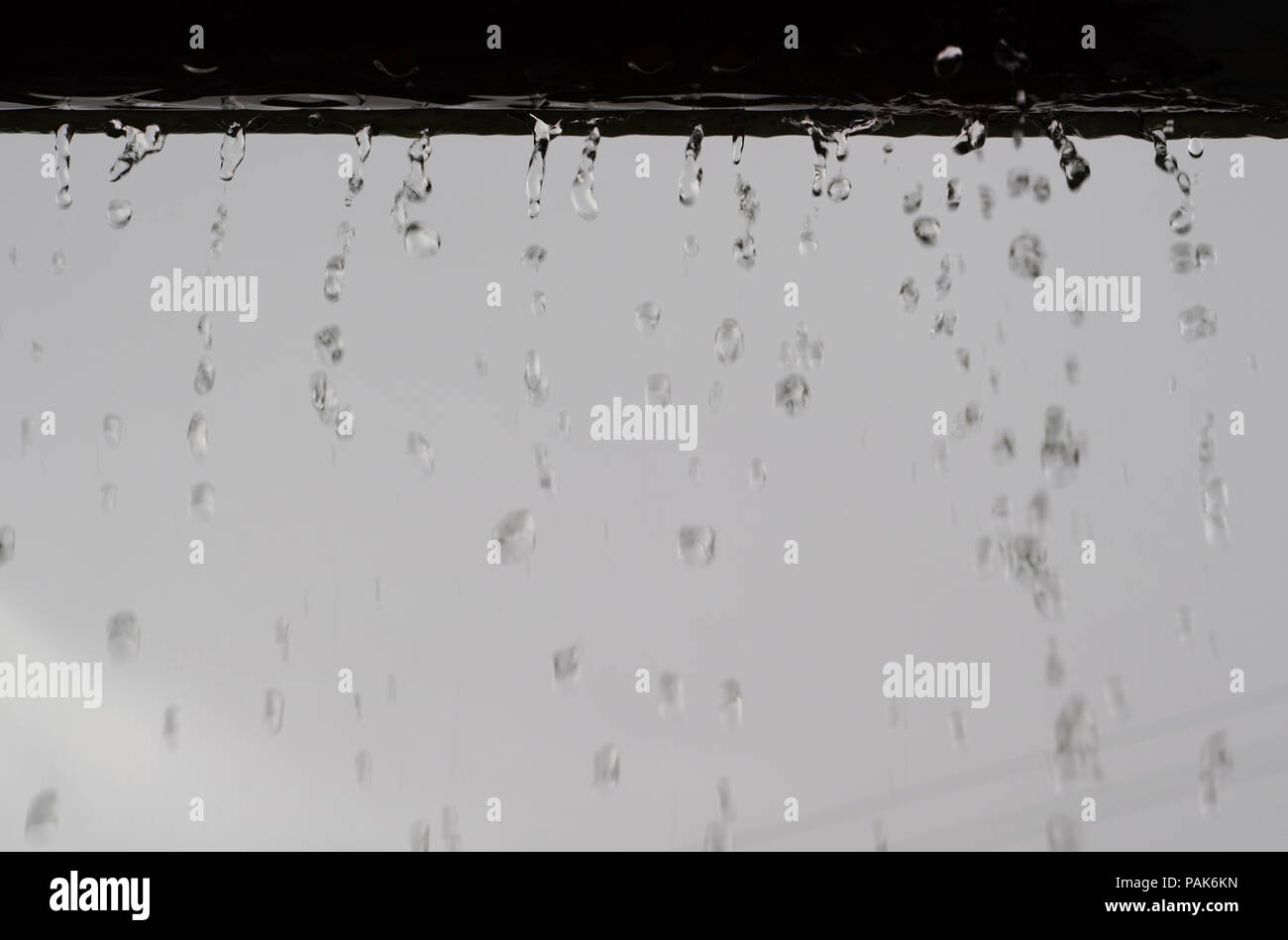 Rain drops fall from the roof end (eave) with natural clear background ...