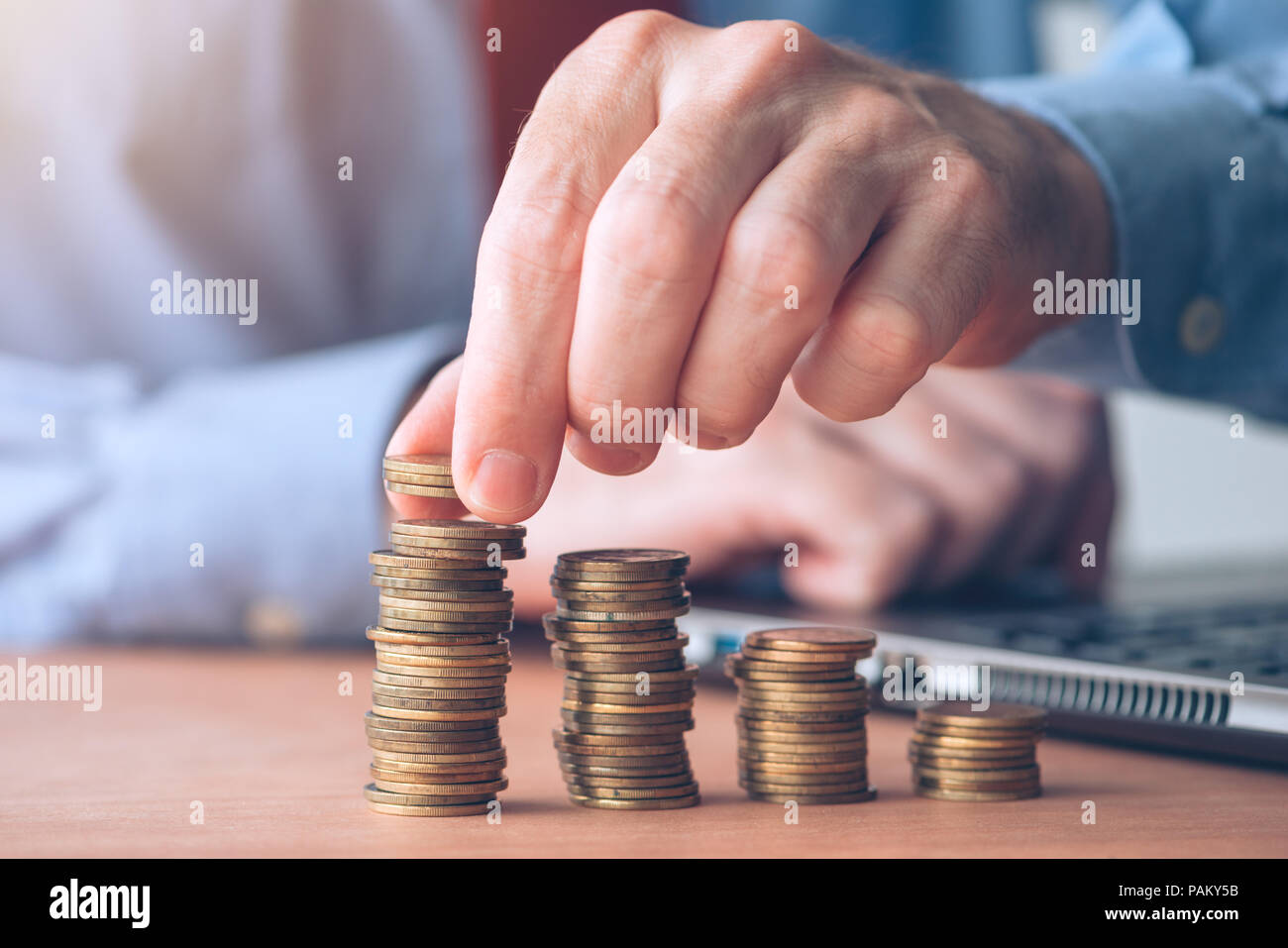 Coin stacker, businessman with stacked money in the office doing ...