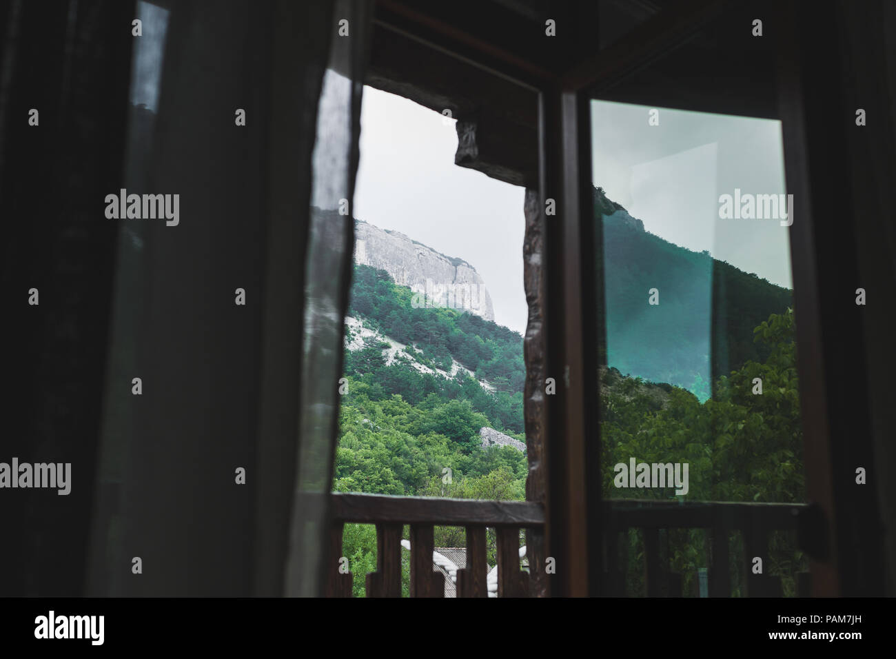 Mountain view through open window on balcony, rocks in cloudy and foggy ...