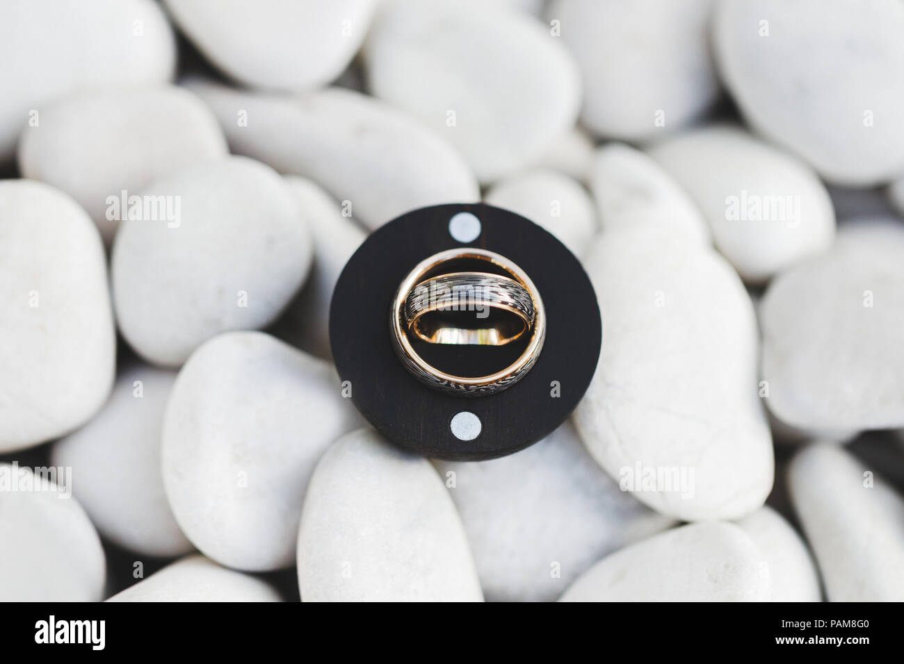 Wedding rings in round black box on white pebble stone background Stock ...