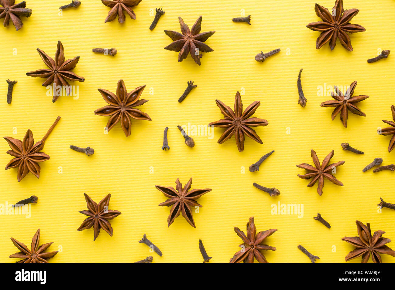 composition of star anise and cloves on a yellow background. Abstract ...