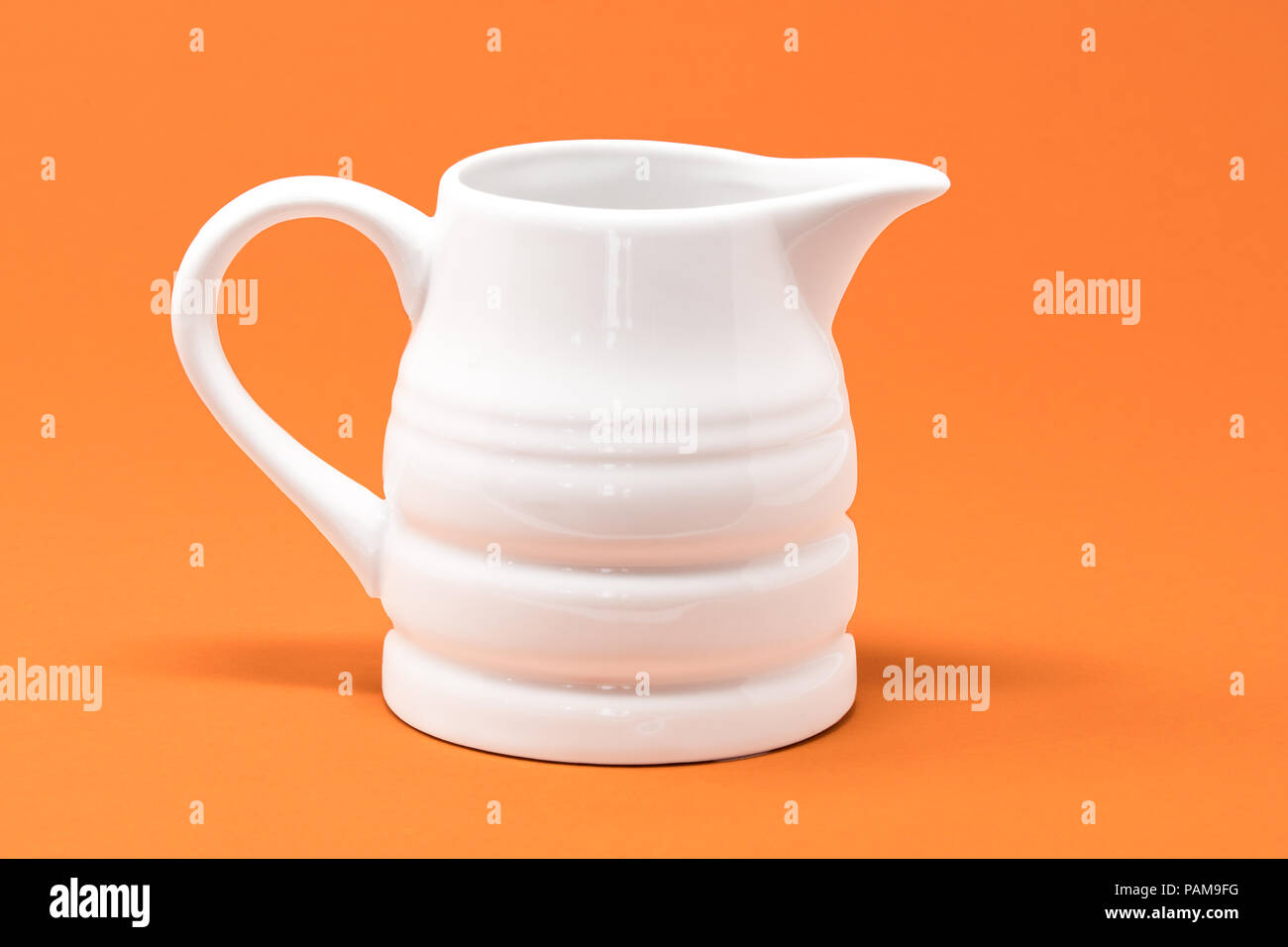 A white jug set against a bright orange background Stock Photo - Alamy