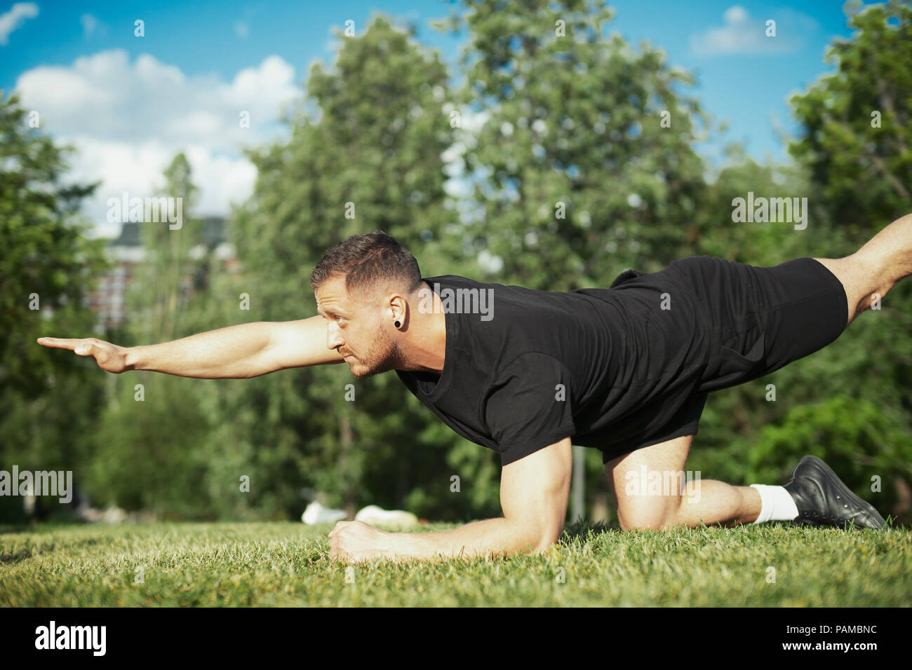 Young attractive man stretching outdoors in the park. Leg and hand are ...