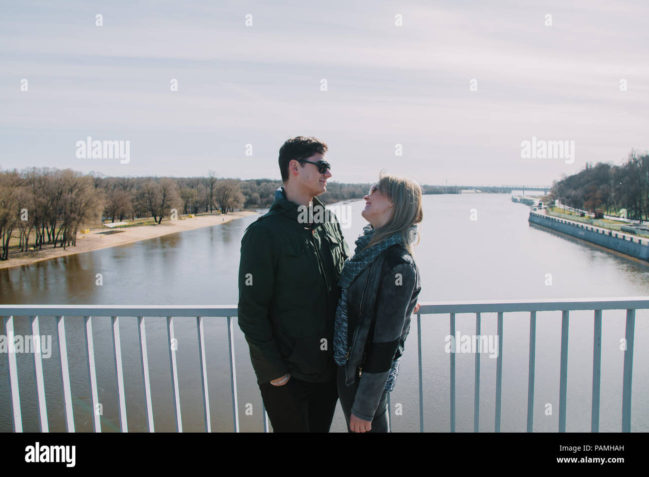 Beautiful loving each other couple is standing on the bridge smiling ...
