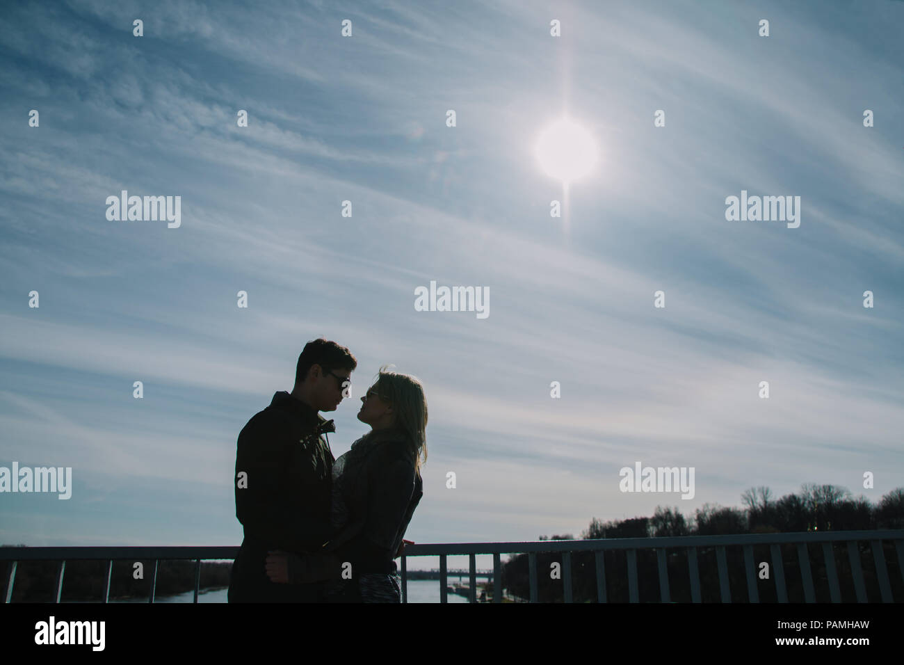 Beautiful loving each other couple is standing on the bridge smiling ...