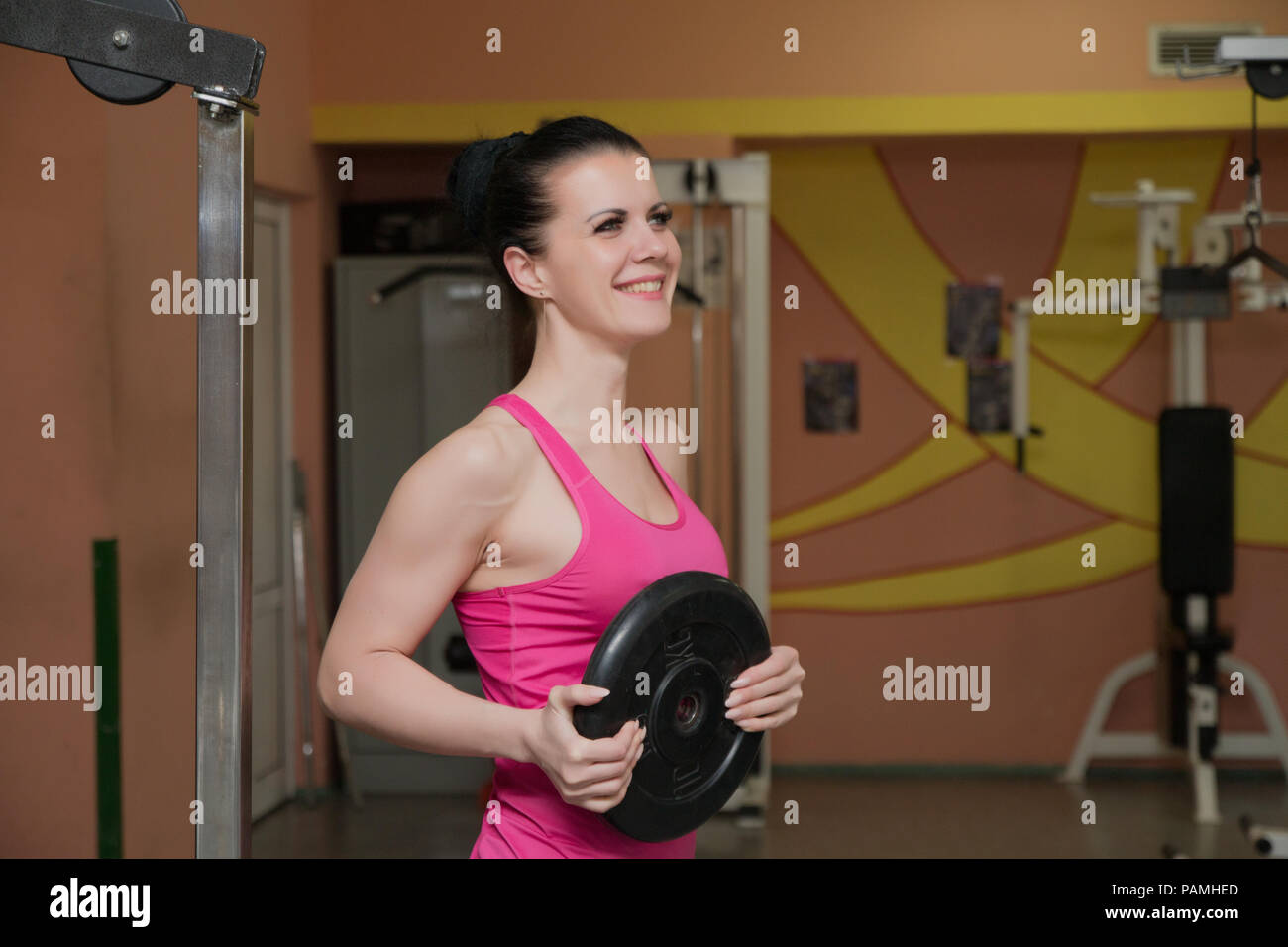 Beautiful girl is standing with a sports equipment in the fitness club ...
