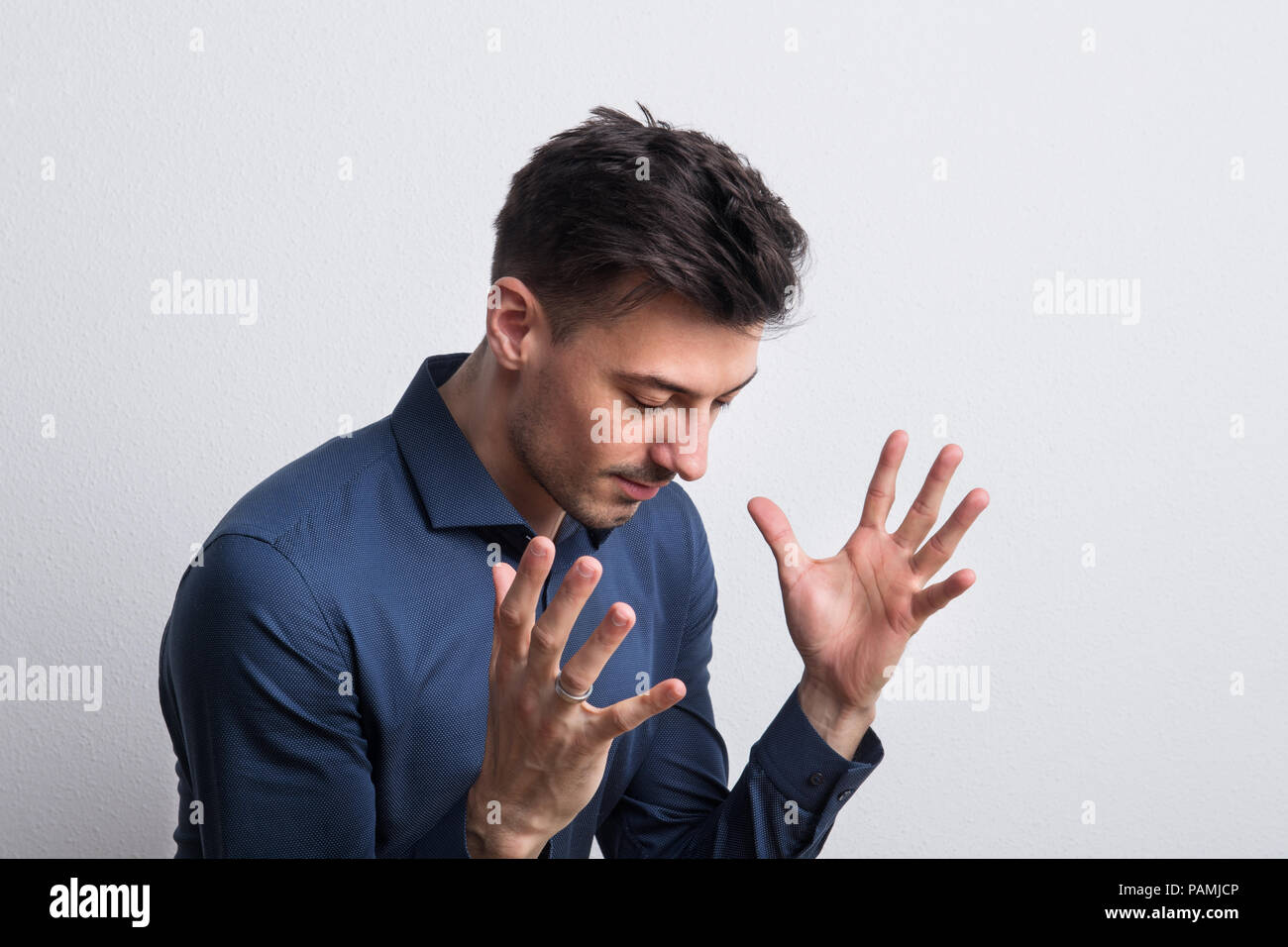 Portrait of a young man in a studio with hands up Stock Photo - Alamy