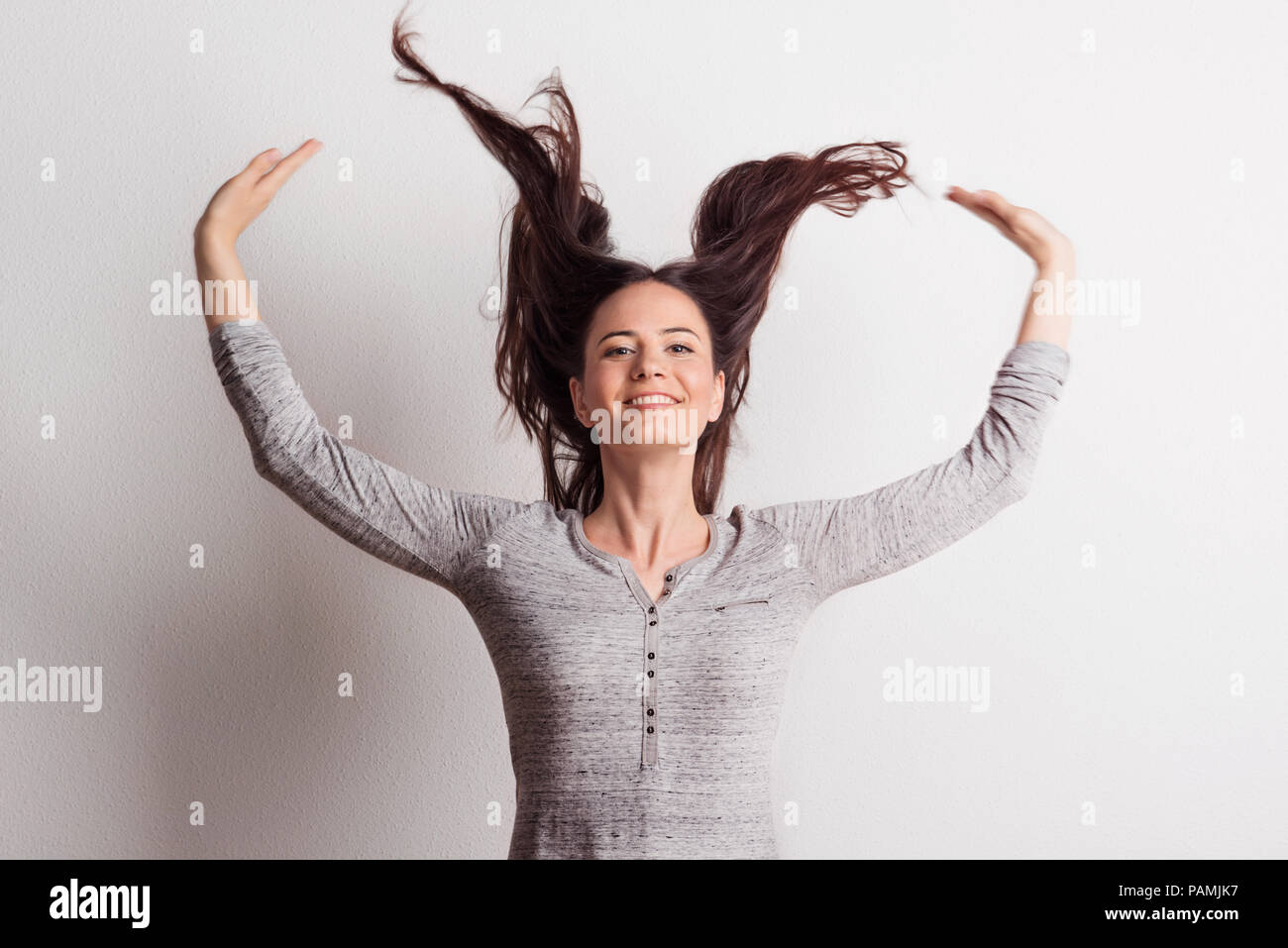 A young beautiful delighted woman in studio with hands and hair in the ...