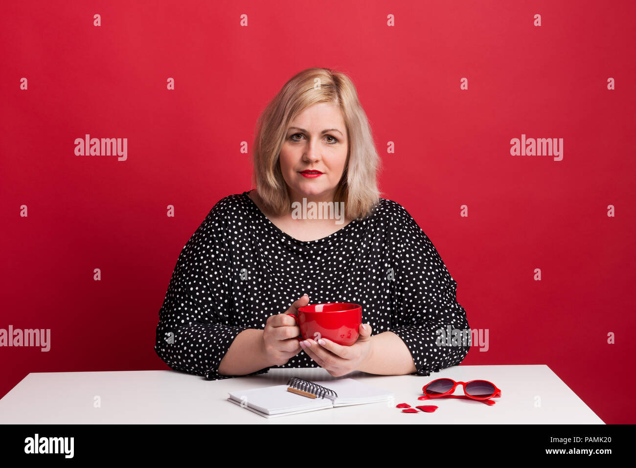Portrait of an attractive overweight woman in studio on a red ...