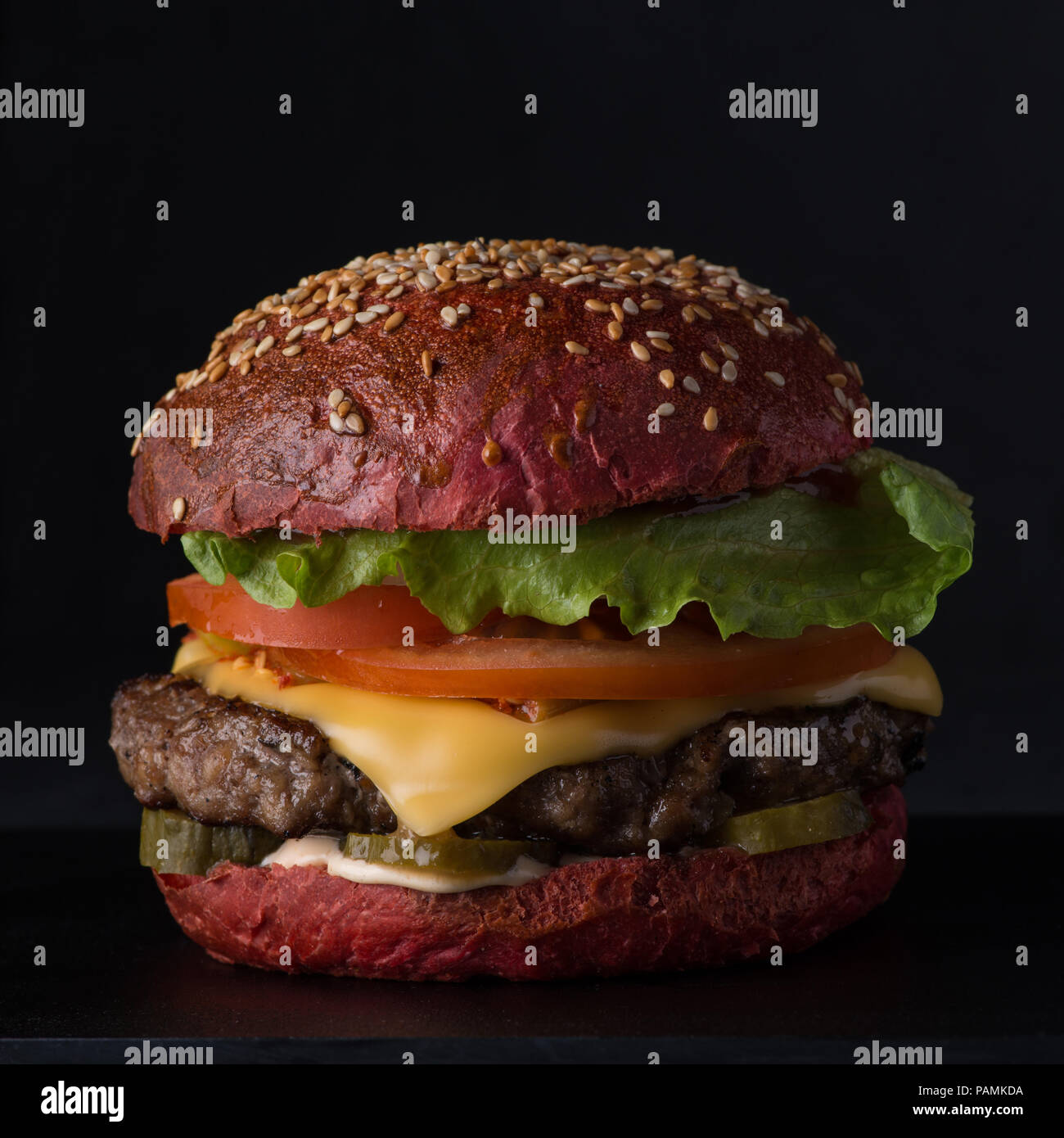 juicy cheeseburger of red bread on a black background, close-up Stock ...