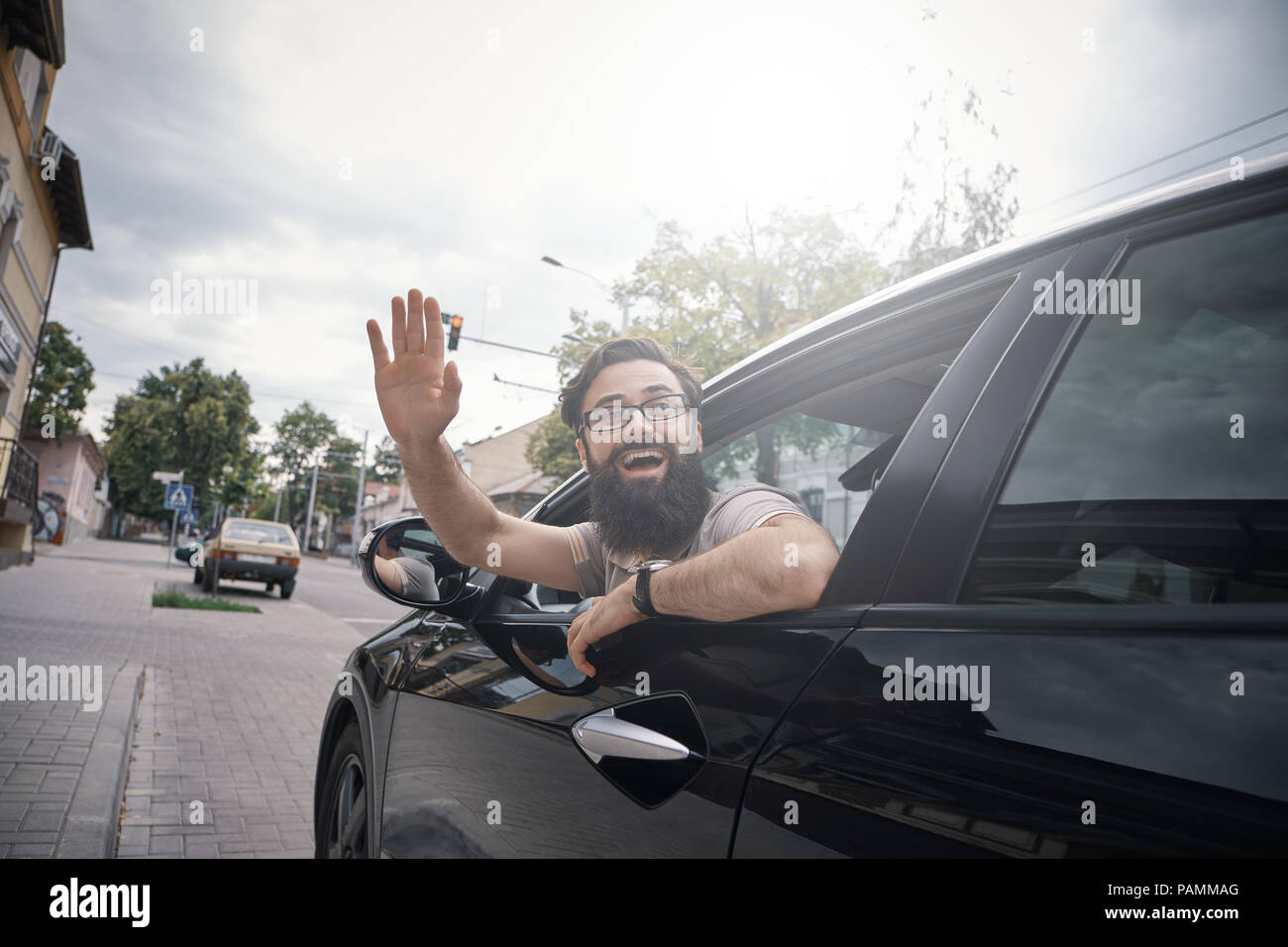 Cheerful man waving while driving a car Stock Photo - Alamy