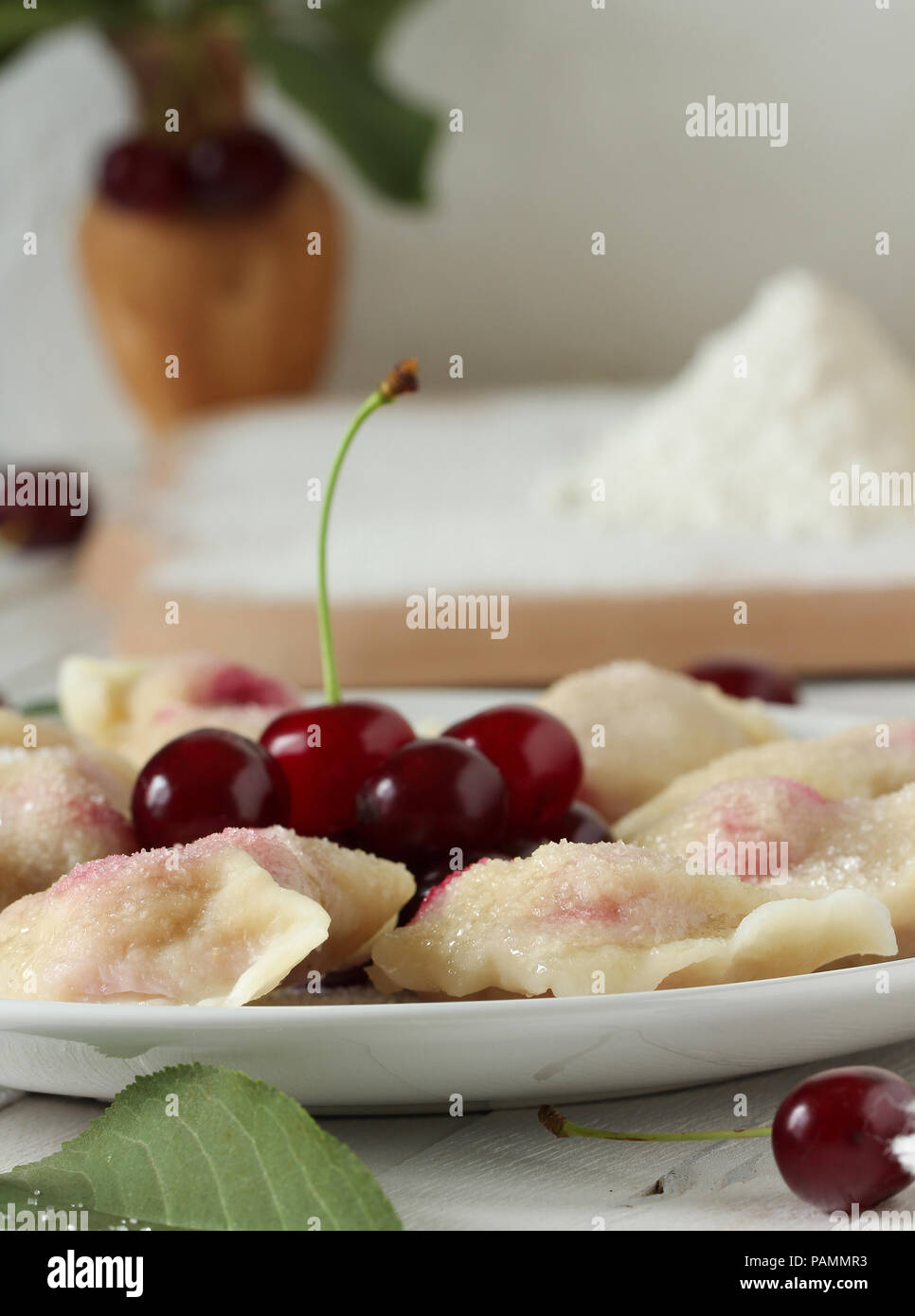 Vareniki (pierogi) with cherries on a white wooden background ...